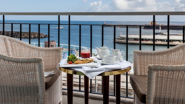 Varanda com cadeiras de vime e mesa posta para o café da manhã.