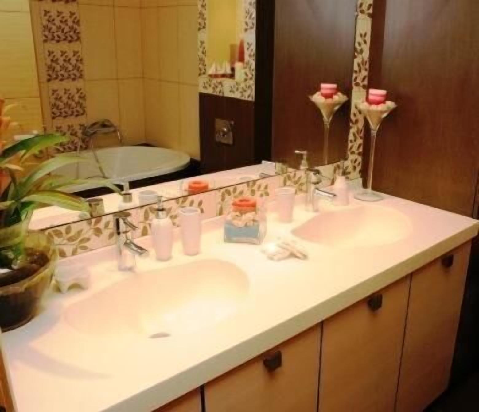 Casa de banho com duas pias, um espelho e uma planta em vaso.
