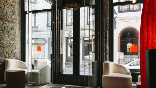 Um saguão de hotel moderno com entrada por porta de vidro, assentos confortáveis e vista para a rua.