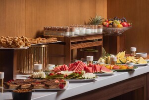 Buffet com diversos doces, frutas e bebidas.