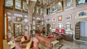 Um quarto ricamente decorado, com paredes elaboradas, amplas janelas e mobiliário tradicional.