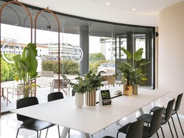 Uma sala de jantar moderna com uma mesa branca, cadeiras pretas e plantas em vasos.