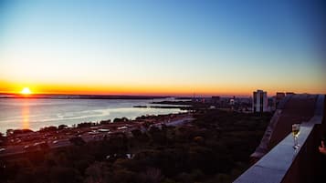 Vista do pôr do sol sobre a água, com o horizonte da cidade ao fundo.