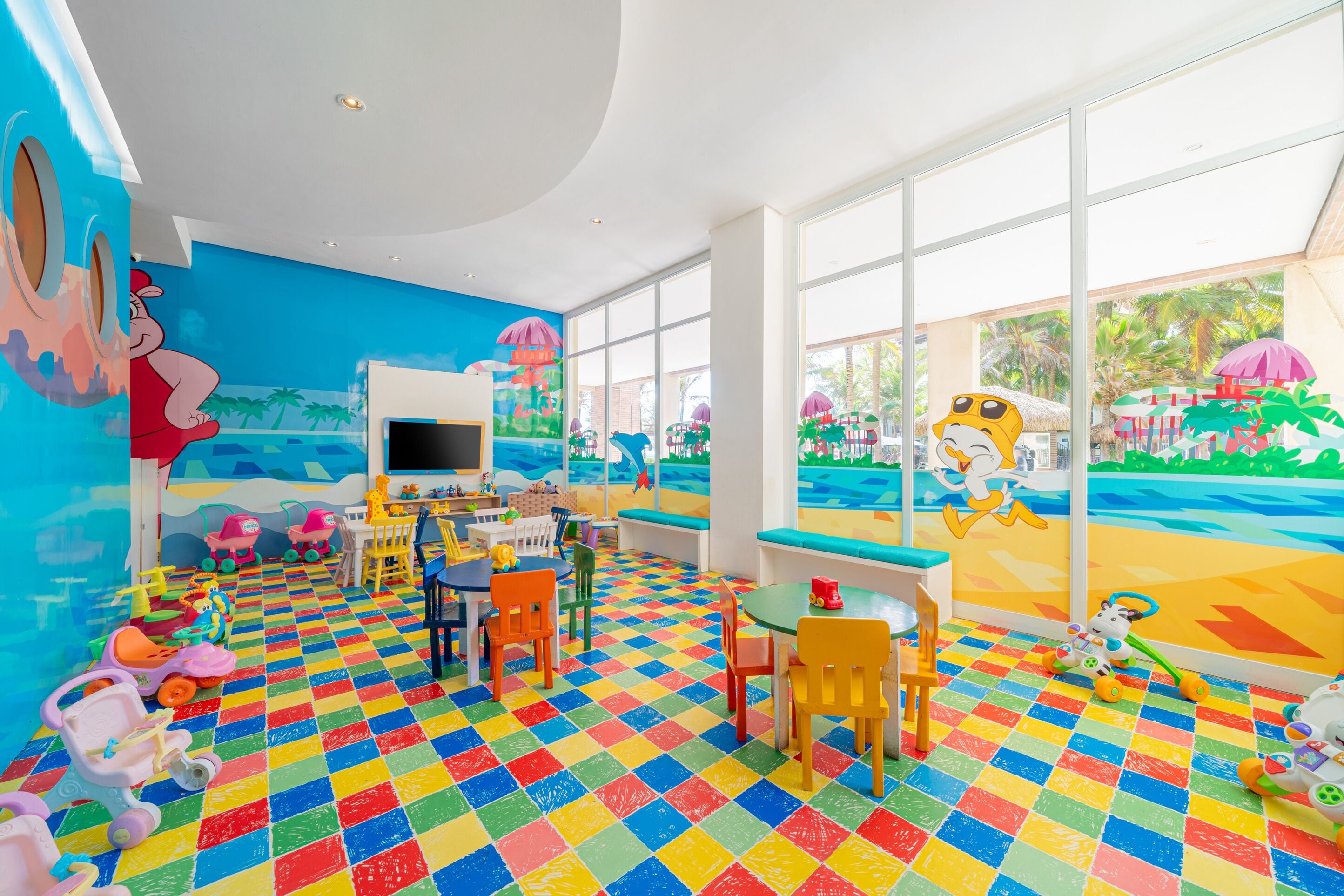 Uma sala de brincadeiras infantil vibrante, com piso xadrez, janelas amplas e murais alegres nas paredes.