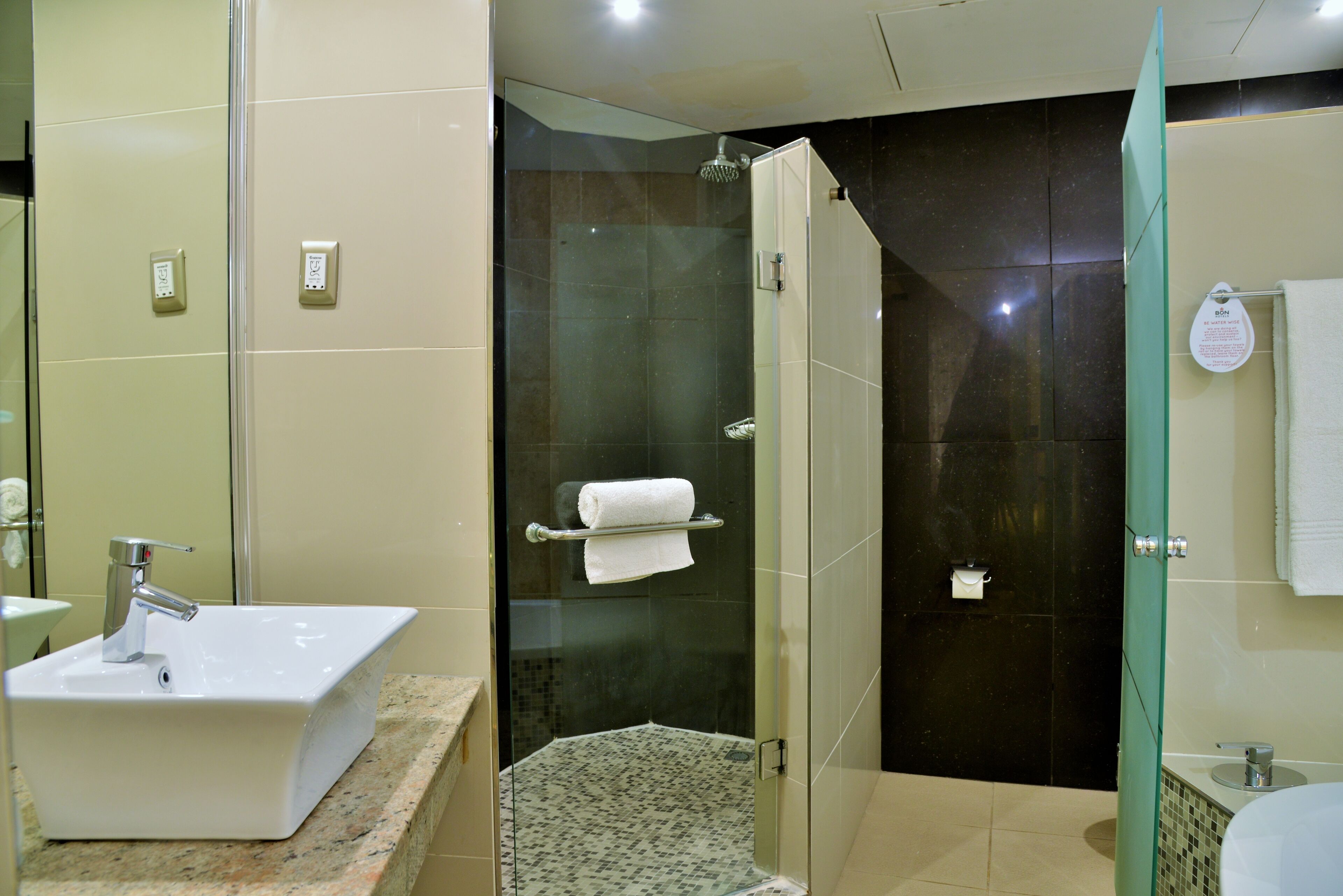 Uma casa de banho moderna com uma grande pia, uma cabine de duche com portas de vidro e um espelho.