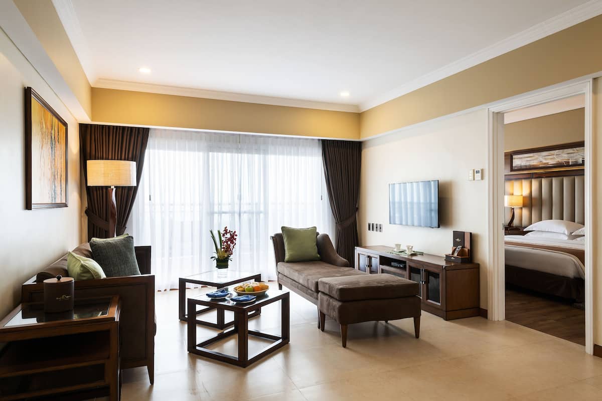 Quarto de hotel moderno com sofá, mesa de centro, televisão, escrivaninha e cama.