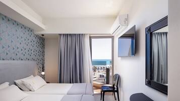 Quarto de hotel com cama, cadeira, televisão e vista para a praia.