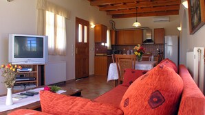 Uma sala de estar acolhedora com um sofá, televisão e um espaço de jantar com mesa e cadeiras.