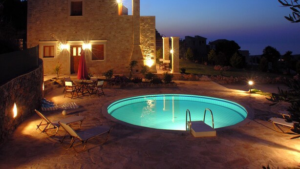 Um edifício de pedra com piscina, área de estar externa e um pátio bem iluminado.
