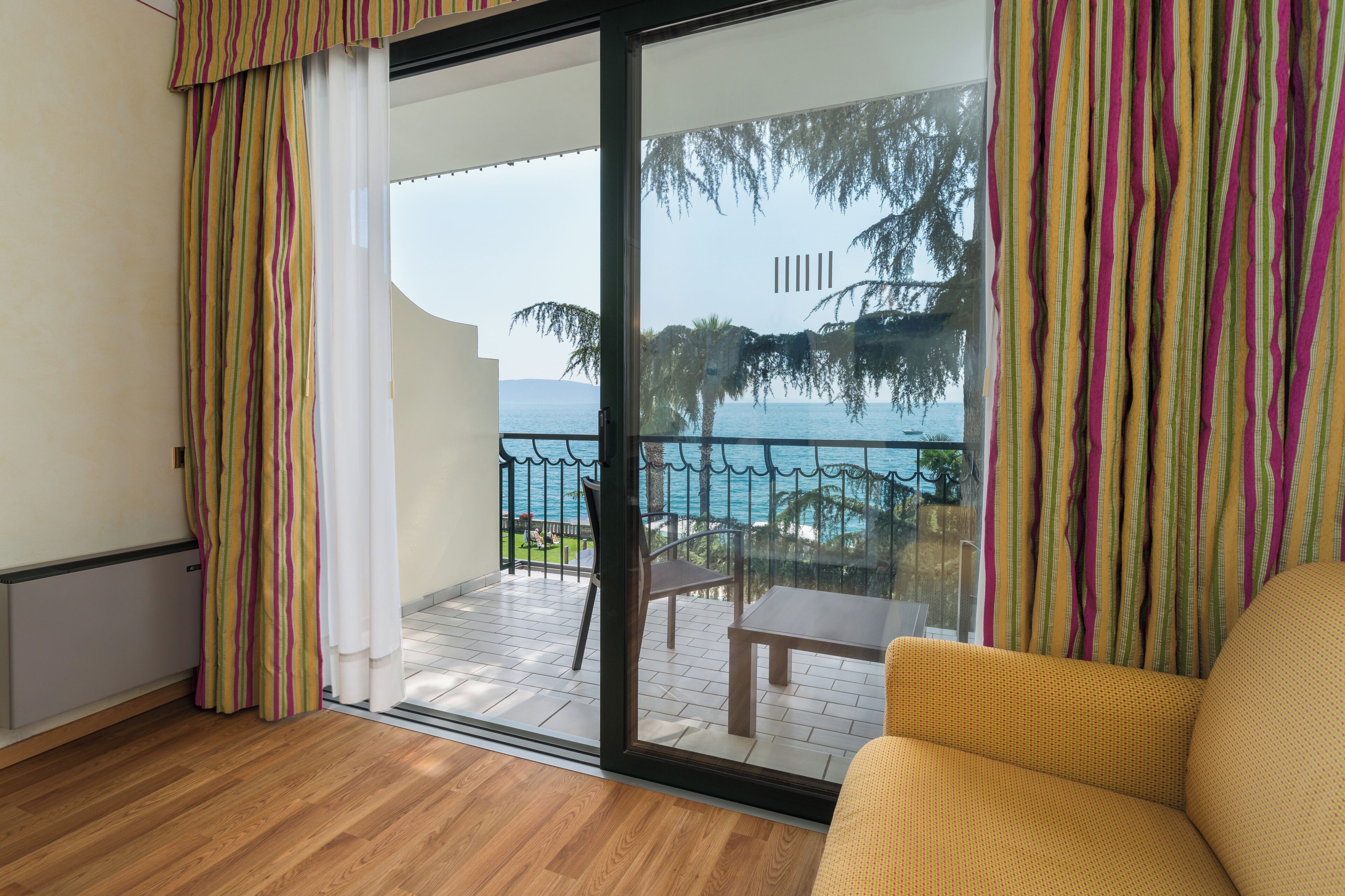 Uma varanda com vista para o mar, uma porta de correr de vidro e um sofá amarelo.