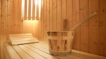 Uma sauna de madeira com bancos e um balde de madeira com concha.
