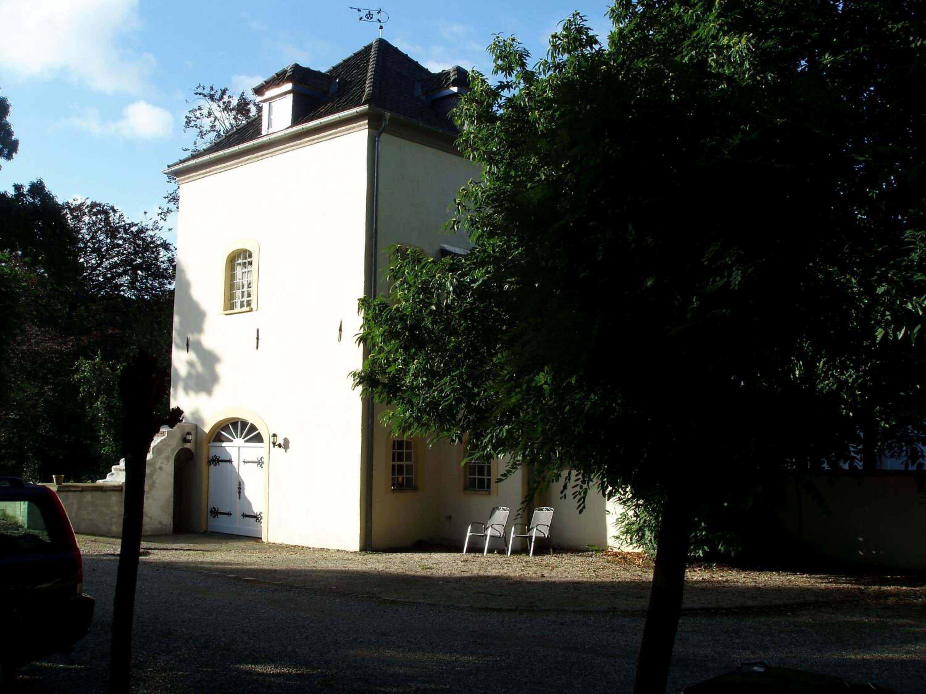 Um edifício de dois andares com fachada branca, uma pequena varanda e uma porta com puxador decorativo.