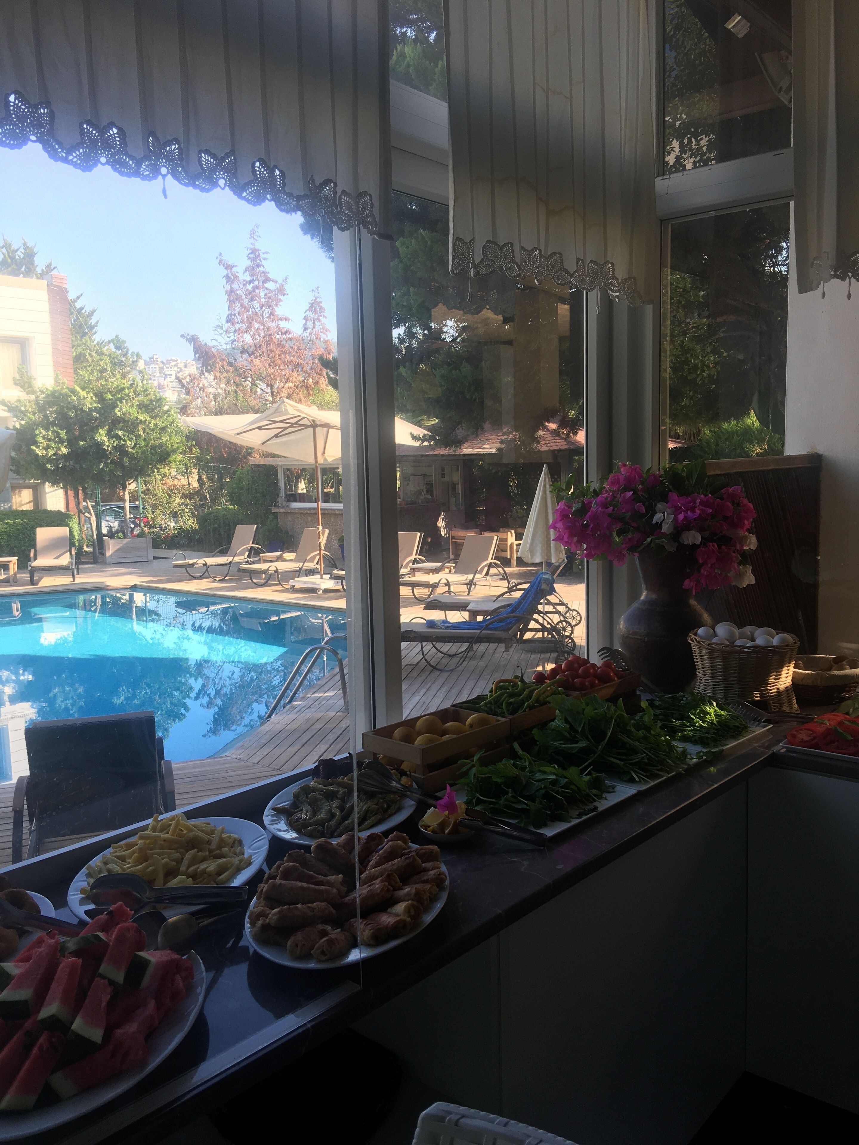 Buffet à beira da piscina com diversos alimentos e vista para a área da piscina.