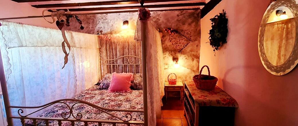 Um quarto aconchegante com uma cama, uma mesinha e um espelho fixado na parede.