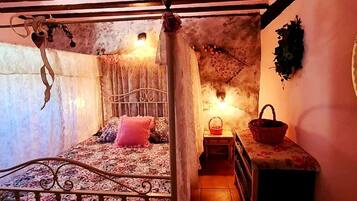 Um quarto aconchegante com uma cama, uma mesinha e um espelho fixado na parede.