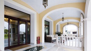 Um hall de hotel com piso de mármore, balcão de recepção e área de estar com grade branca.