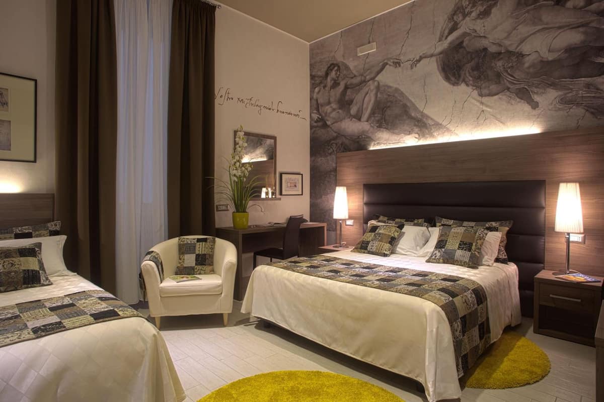 Quarto de hotel com duas camas, uma escrivaninha, uma cadeira, um mural grande e um vaso de planta.