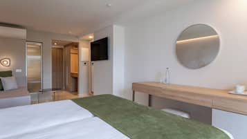 Quarto de hotel moderno com cama, escrivaninha, espelho e televisão.