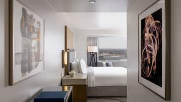 Quarto de hotel com cama, mesa de cabeceira, abajur e obras de arte nas paredes.
