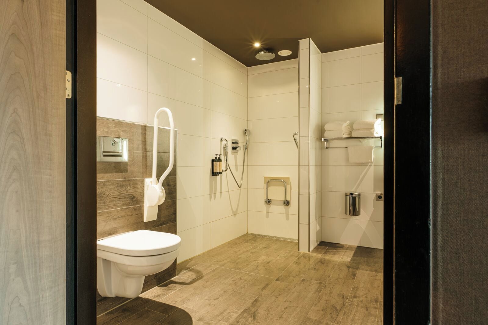 Uma casa de banho moderna com sanita, chuveiro e um porta-toalhas.