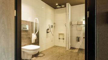 Uma casa de banho moderna com sanita, chuveiro e um porta-toalhas.