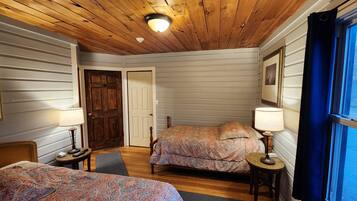 Um quarto aconchegante com duas camas, teto de madeira e uma janela com cortinas.