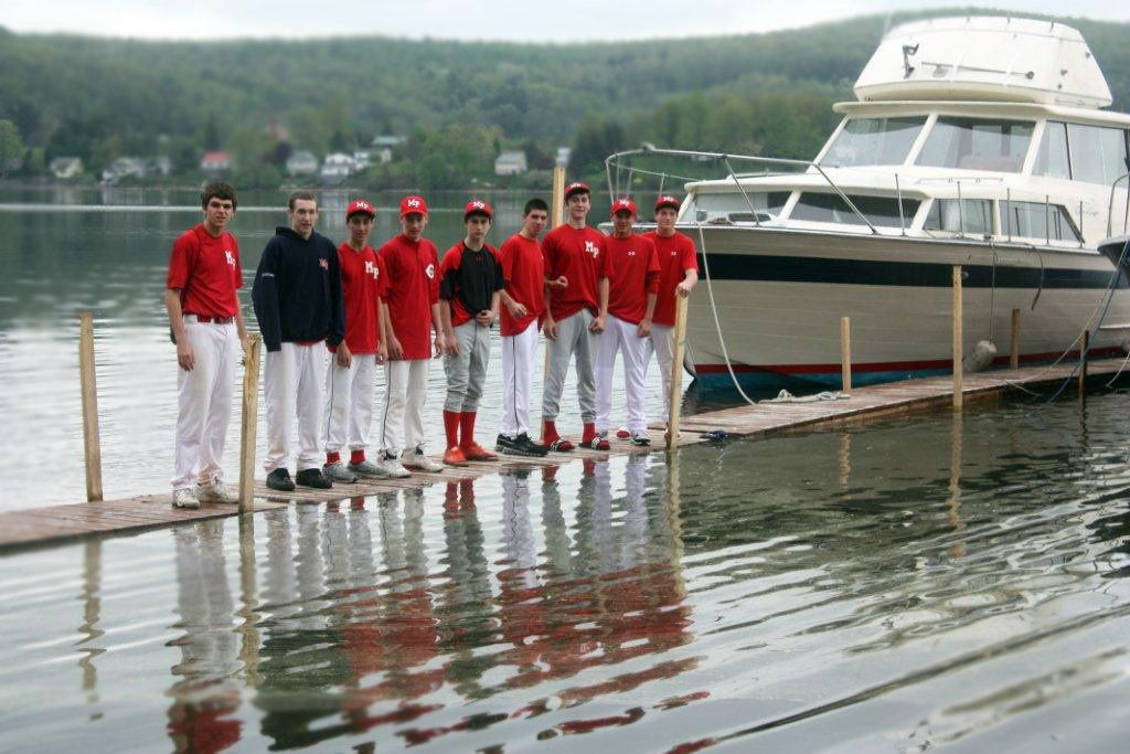 Um grupo de pessoas em um píer, perto de um barco em um lago.