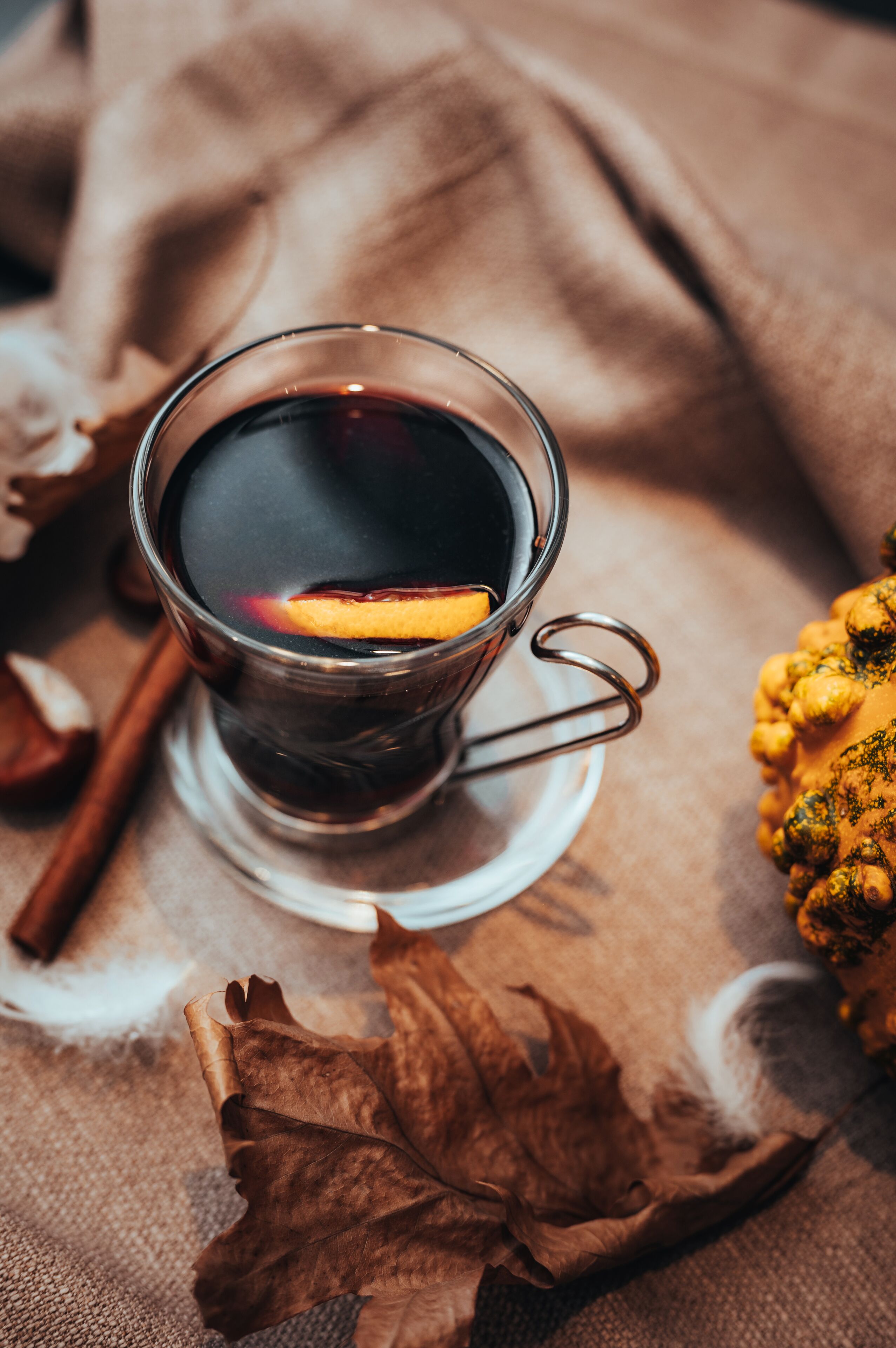 Uma chávena de vidro transparente com um líquido escuro, possivelmente chá ou café, sobre um pires.