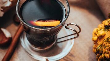 Uma chávena de vidro transparente com um líquido escuro, possivelmente chá ou café, sobre um pires.