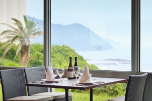 Mesa posta para refeição com vista para montanhas e o mar.