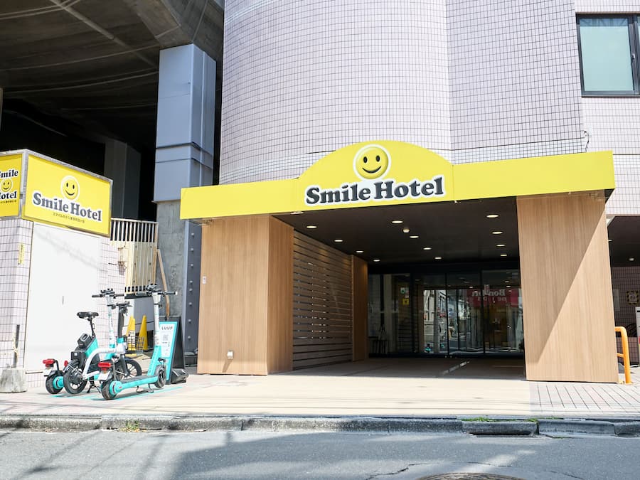 Entrada do Smile Hotel com um grande letreiro amarelo com um rosto sorridente.