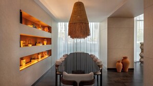 Uma área de jantar moderna com uma mesa redonda, cadeiras acolchoadas e estantes embutidas com objetos decorativos.