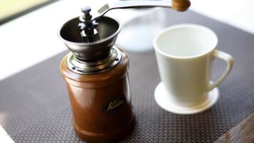 Moedor de café e uma xícara sobre um tapete texturizado.