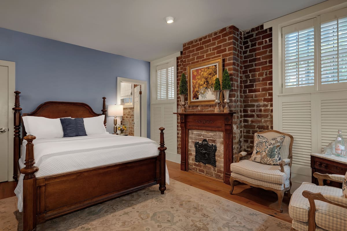 Quarto com cama de madeira, lareira e uma cadeira.