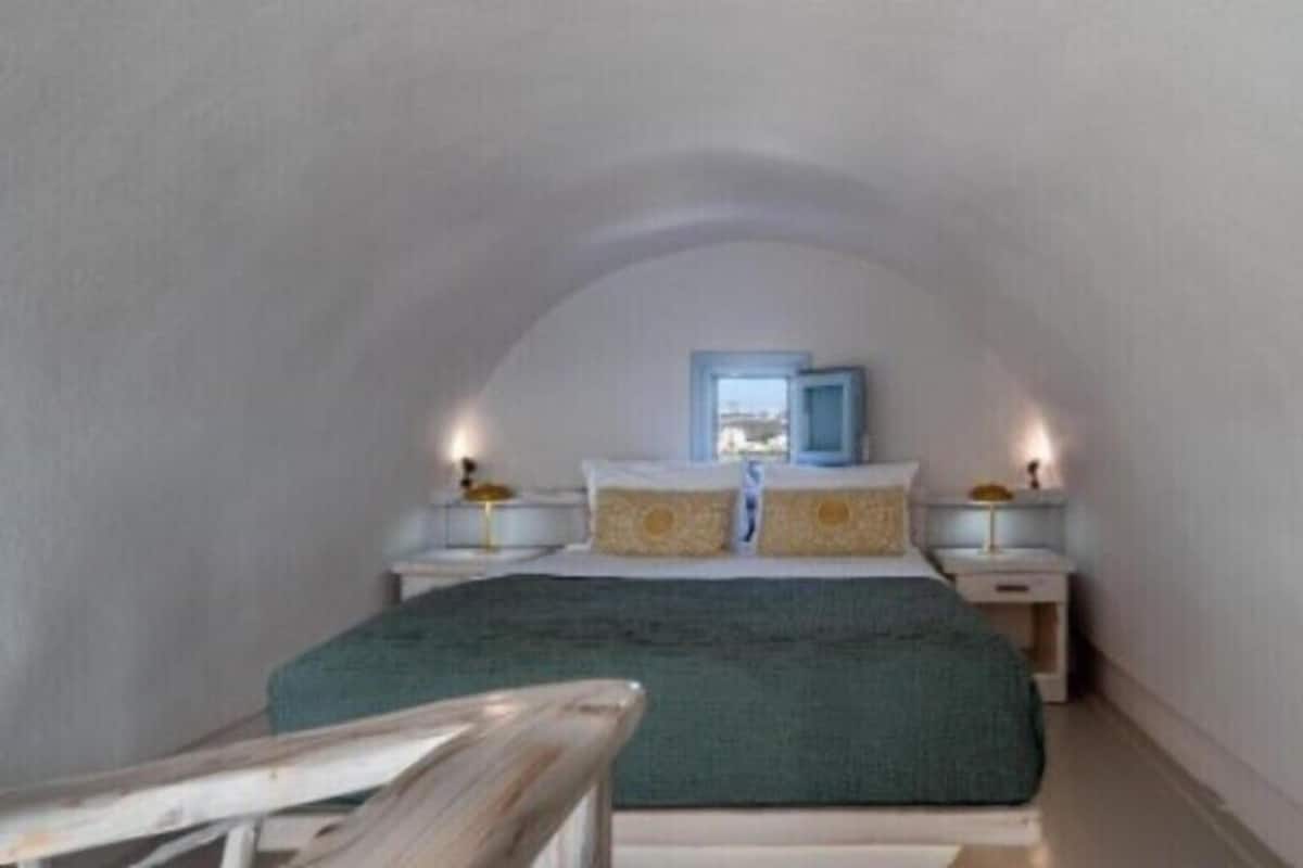 Quarto com uma cama de solteiro, mesas de cabeceira, uma janela e vista para o exterior.