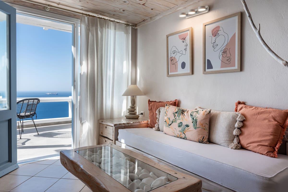 Uma sala de estar moderna com um sofá, uma mesa de centro de vidro e vista para o mar.