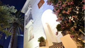 Um edifício com fachada branca, uma varanda com grades pretas e uma placa com o texto 'm suf'.