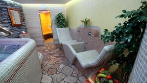 Uma área de spa com piso de pedra, assentos de vime, um espelho e uma cesta de frutas.