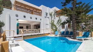 Piscina com espreguiçadeiras e deck de madeira.