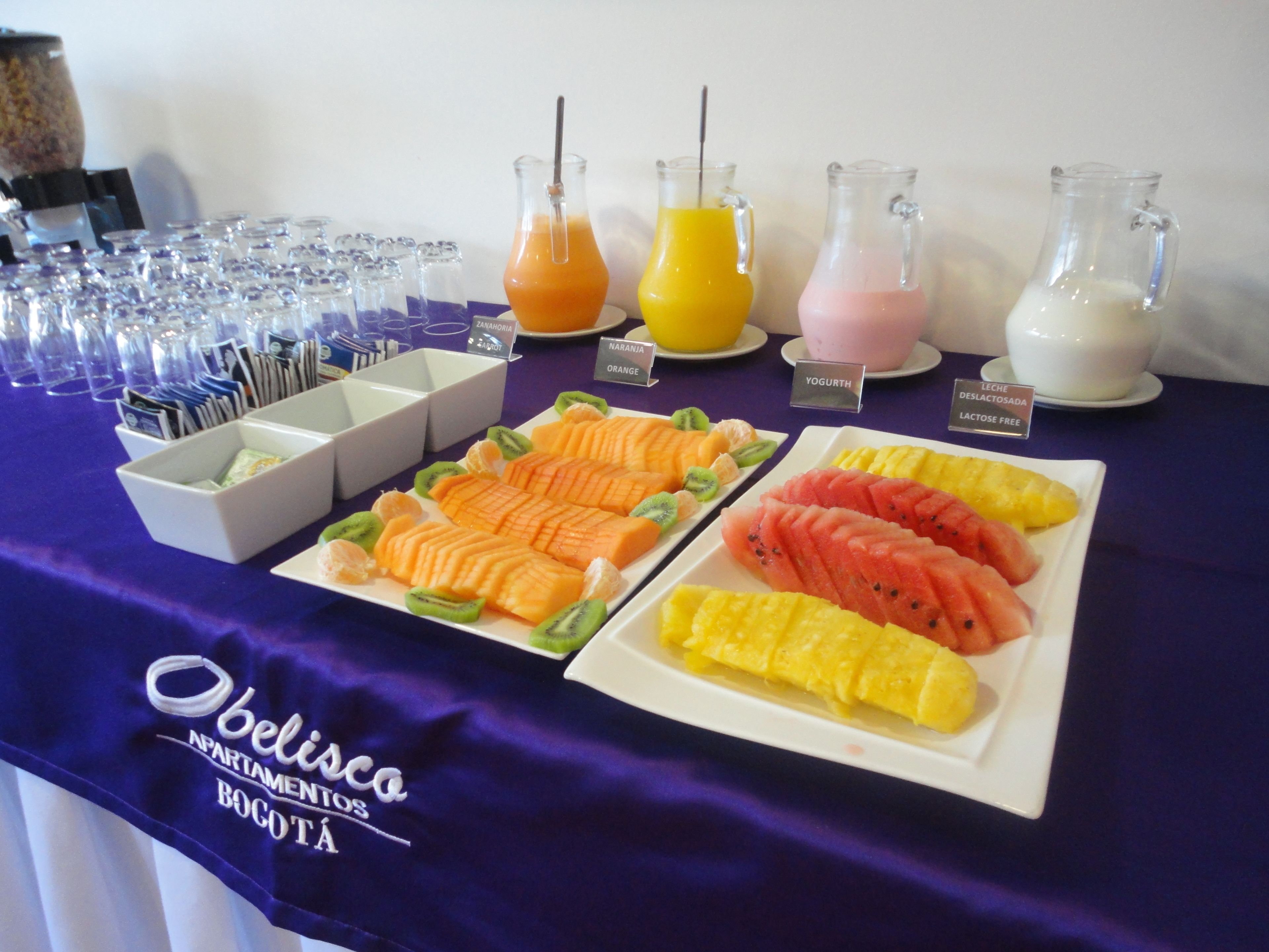 Uma mesa de buffet com diversas frutas e bebidas.