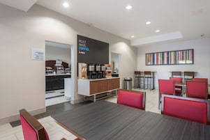 Espaço de café da manhã moderno com estação de café, assentos e aviso com os horários do café da manhã cortesia.