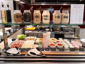 Buffet com diversas opções de comida, incluindo carnes, queijos e uma variedade de molhos e acompanhamentos.