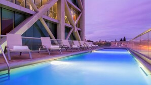 Um edifício moderno com piscina e cadeiras de lounge.