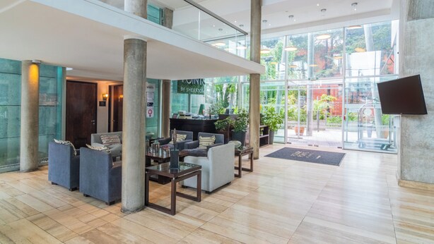 Um hall amplo com área de estar, balcão de recepção e grandes janelas com vista para o exterior.