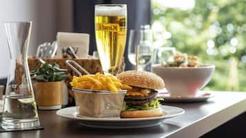Uma mesa de jantar com um hambúrguer, batatas fritas e um copo de cerveja.