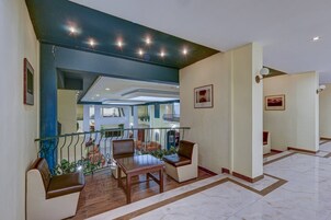 Um hall espaçoso com teto alto, escada e área de estar com mesa e cadeiras.