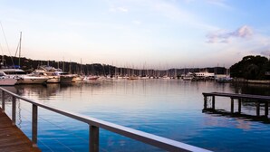 Uma marina com vários barcos atracados, um cais de madeira e águas calmas refletindo o céu.