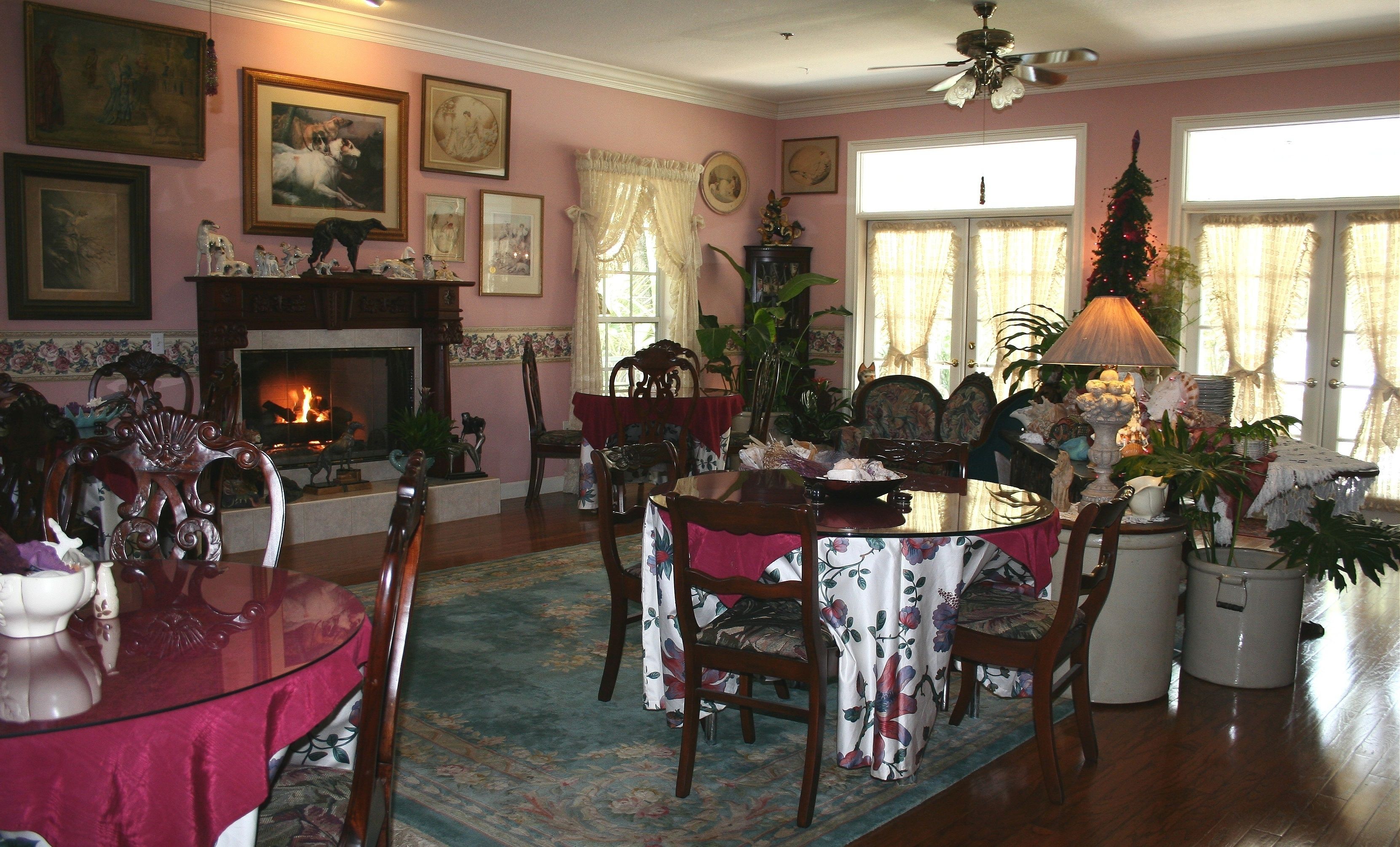 Uma sala de jantar com lareira, papel de parede floral e um pinheiro de Natal.