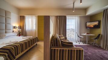 Quarto de hotel com cama, sofá, escrivaninha e cadeira.