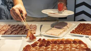 Buffet com diversos tipos de carne e um copo de bebida vermelha.